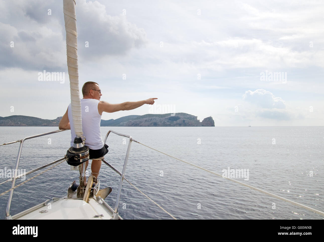 Man sits as a lookout at the bow of a sailing yach Stock Photo - Alamy
