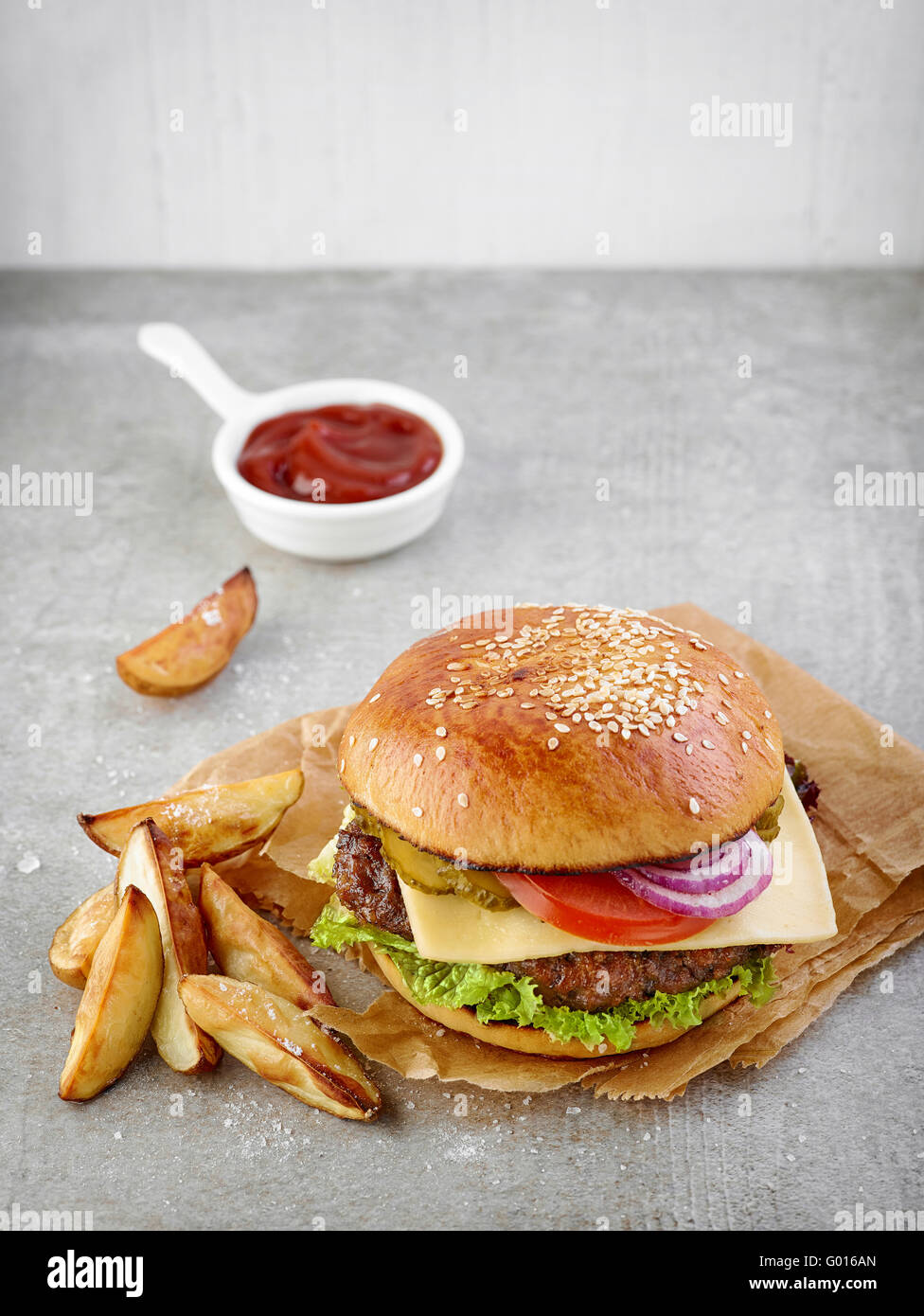 Classic cheeseburger and potato wedges on gray table Stock Photo - Alamy