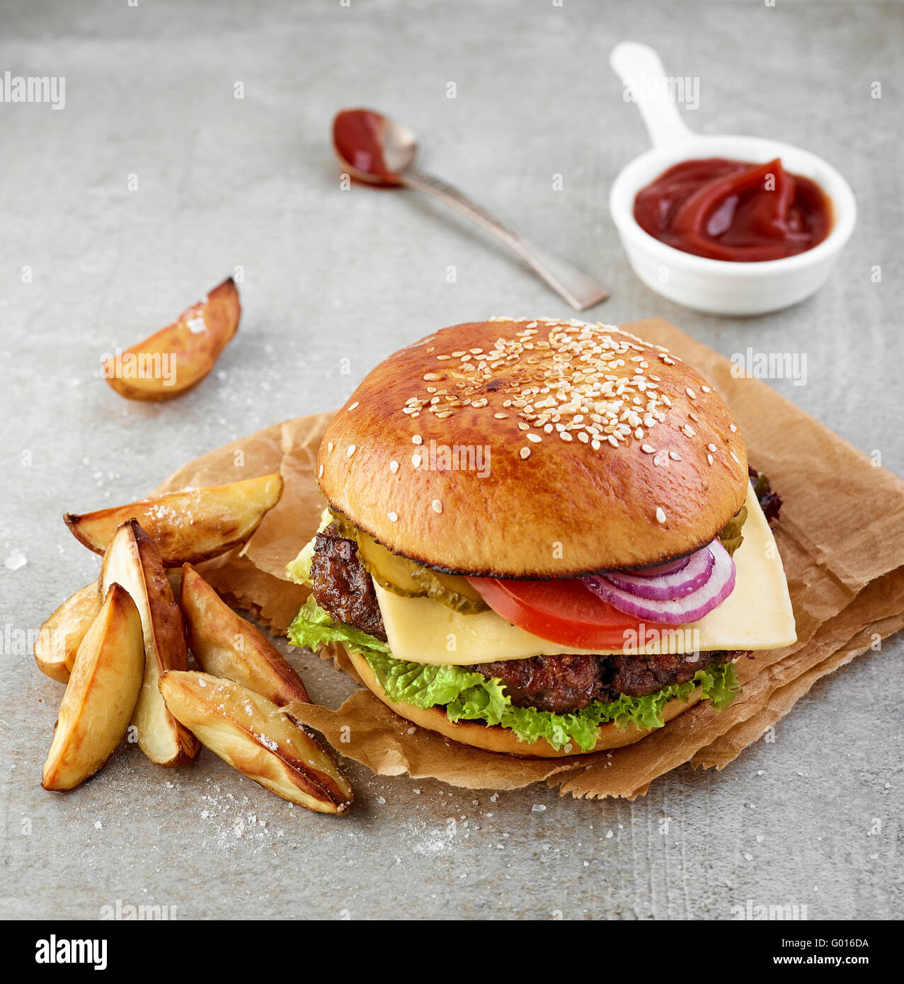 Classic cheeseburger and potato wedges on gray table Stock Photo - Alamy