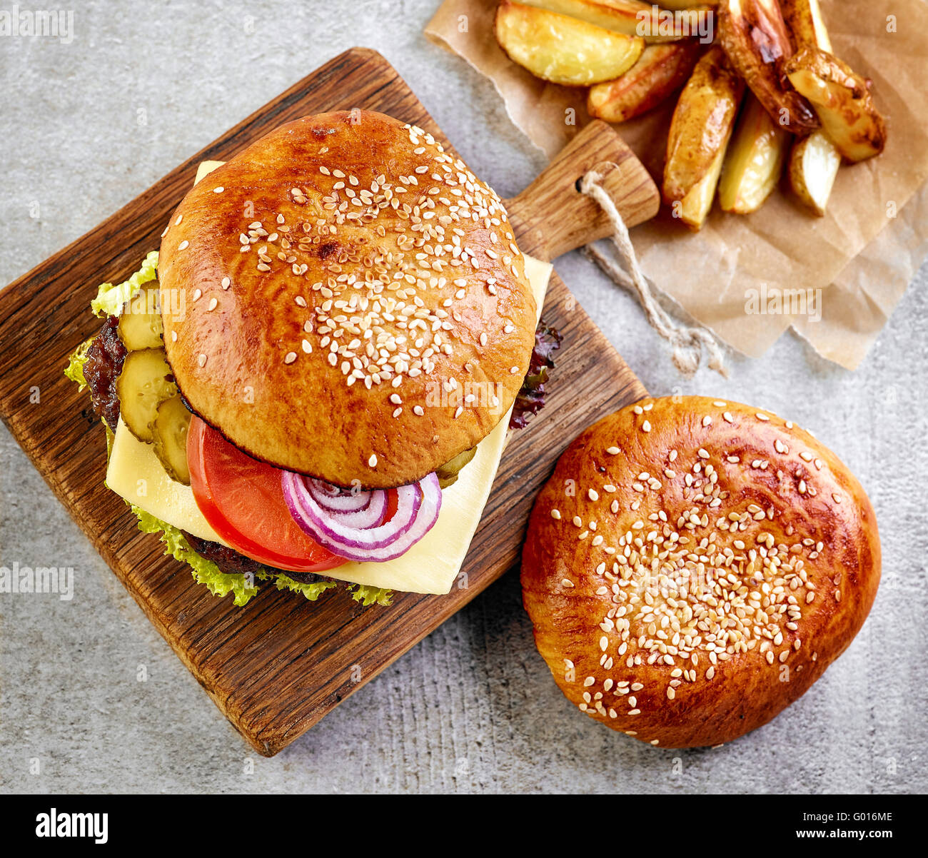 Classic cheeseburger and potato wedges on gray table, top view Stock ...