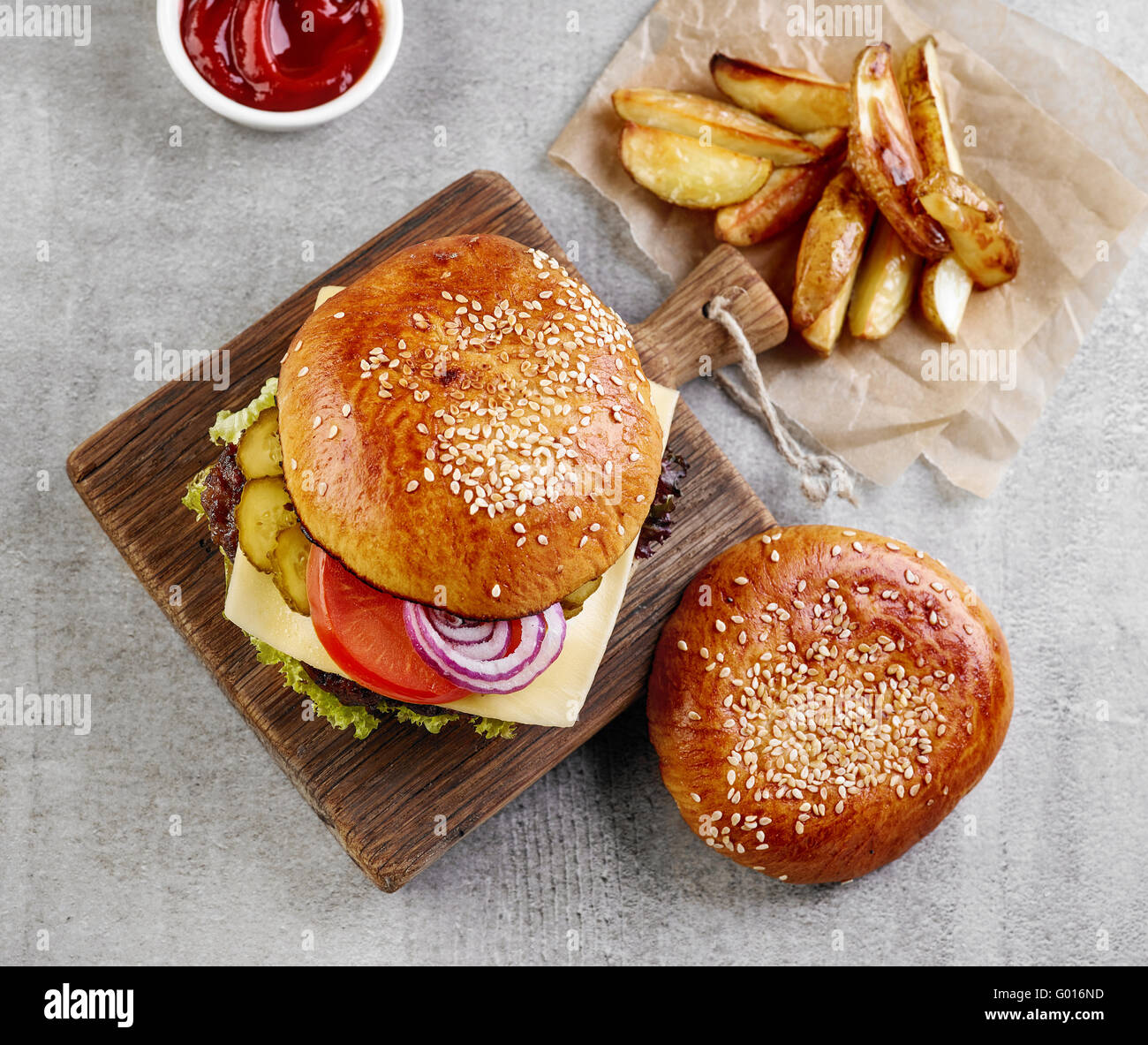 Classic cheeseburger and potato wedges on gray table, top view Stock ...