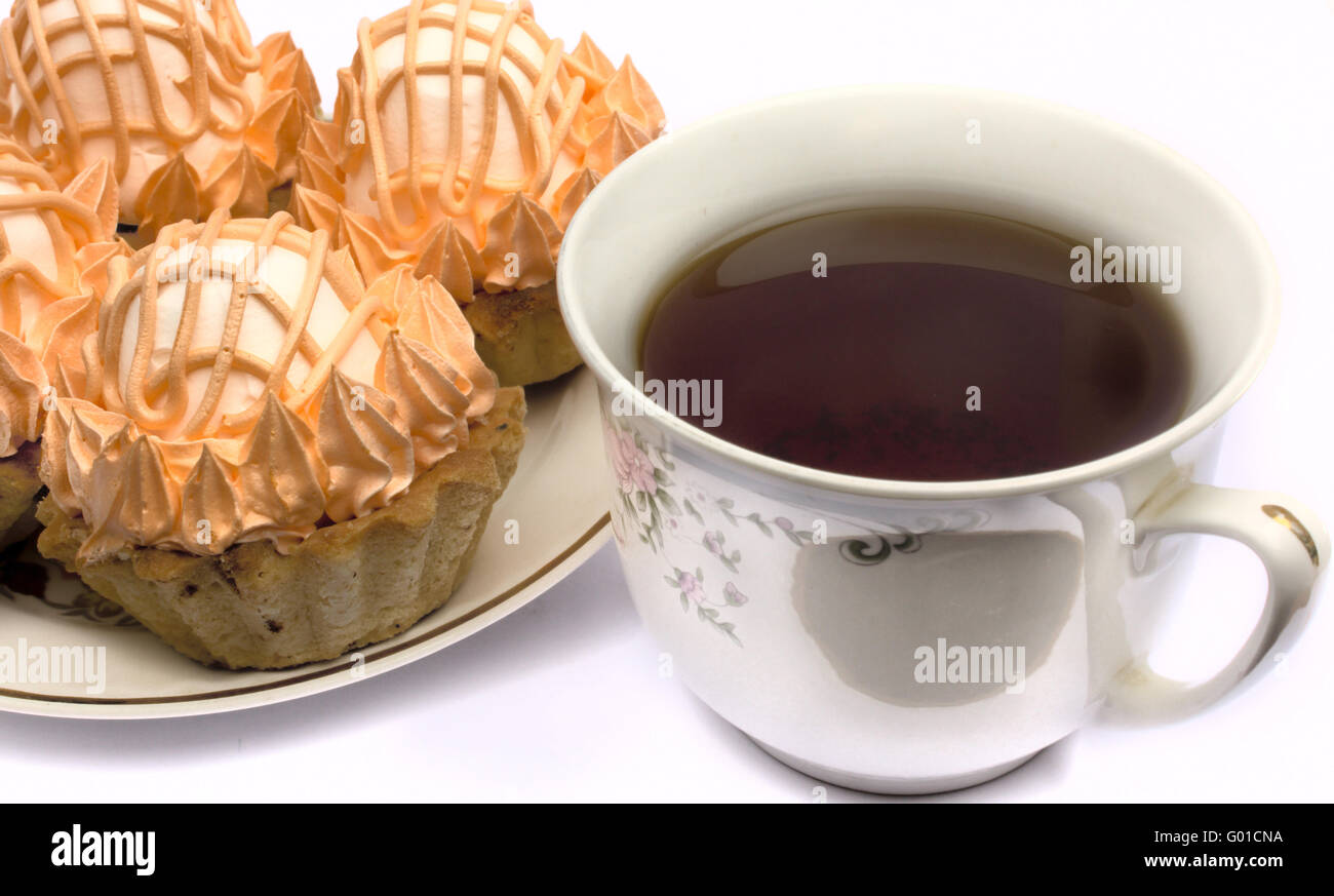 Cup of tea and cakes on a plate on a white background it is isolated ...