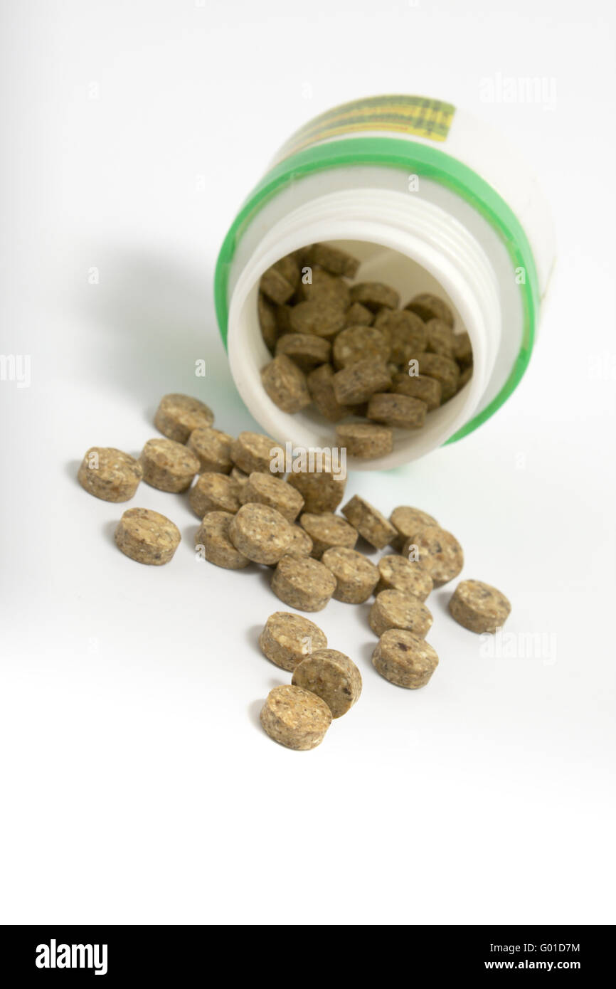 Heap of grassy tablets with a jar on a white background Stock Photo - Alamy
