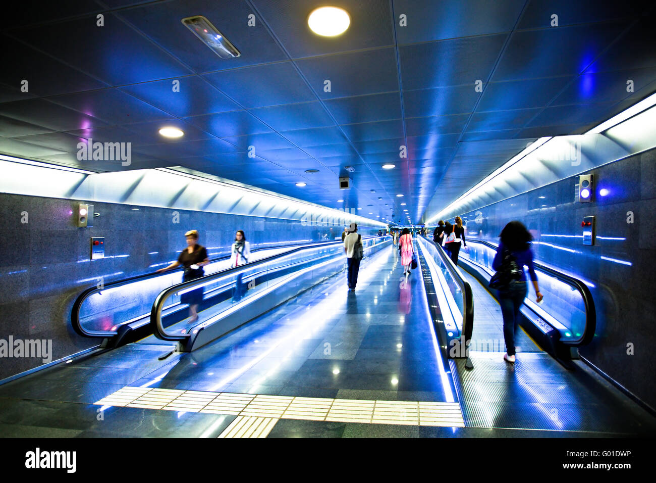 View to blue corridor with escalators and people going on it Stock ...