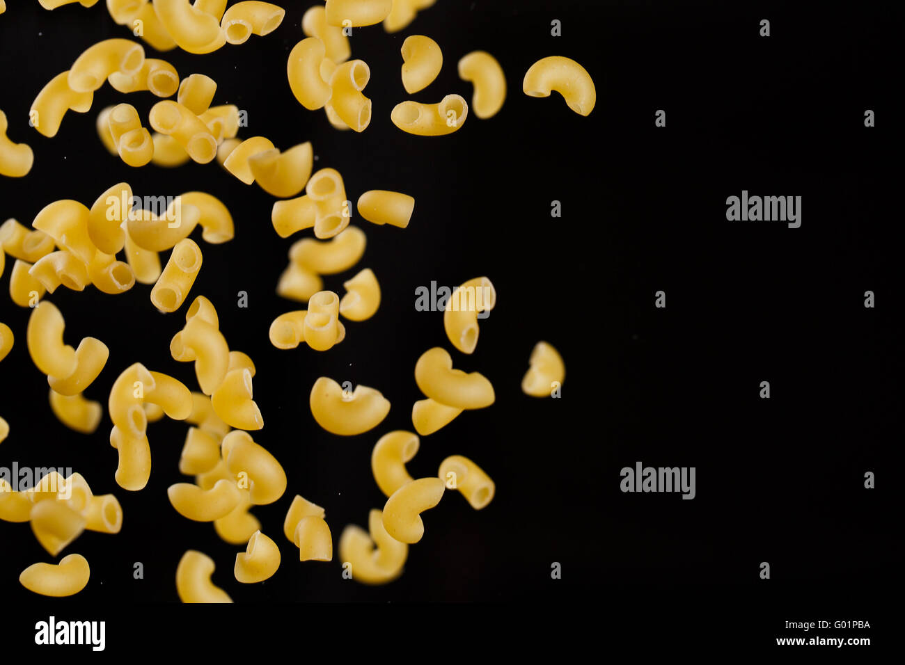 Falling gobetti pasta. Flying yellow raw macaroni over black background ...
