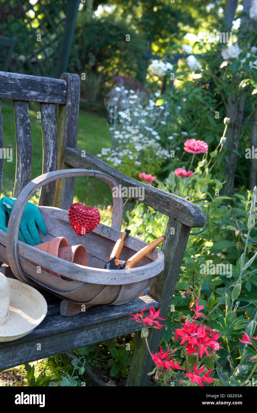 Rustic garden chair in sunlit floral garden with traditional trug ...