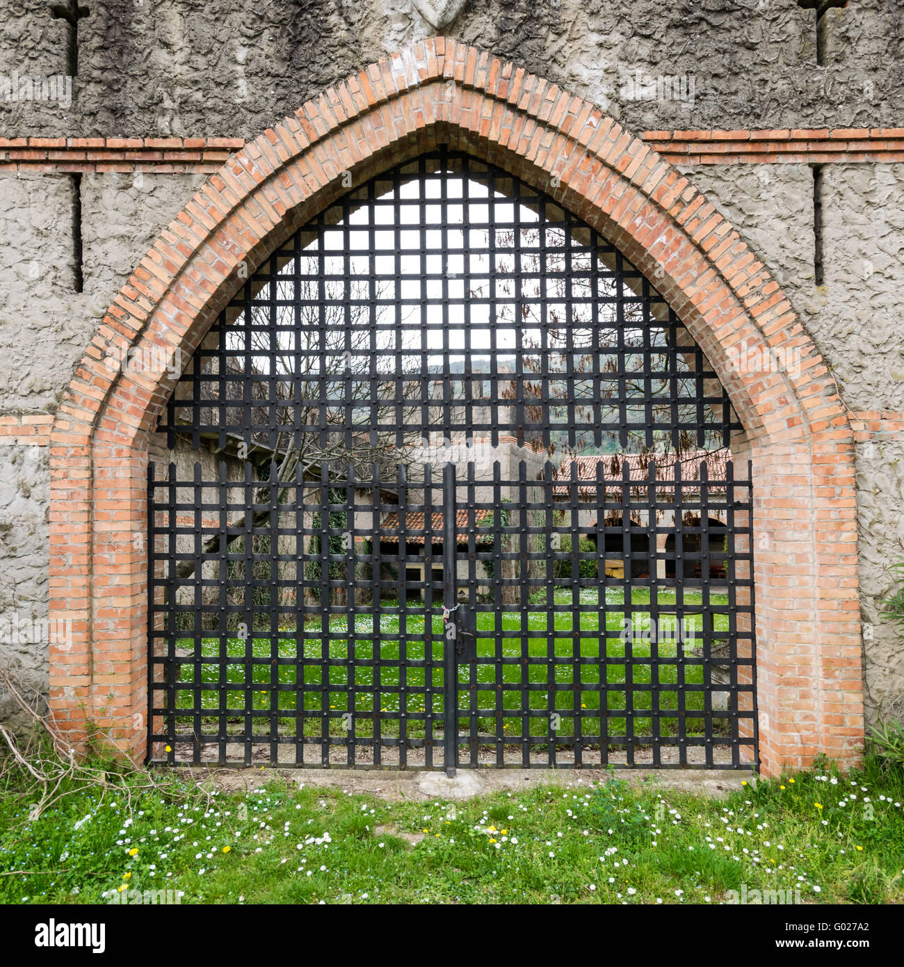 arched entrance of a medieval castle closed by an iron grille gate ...