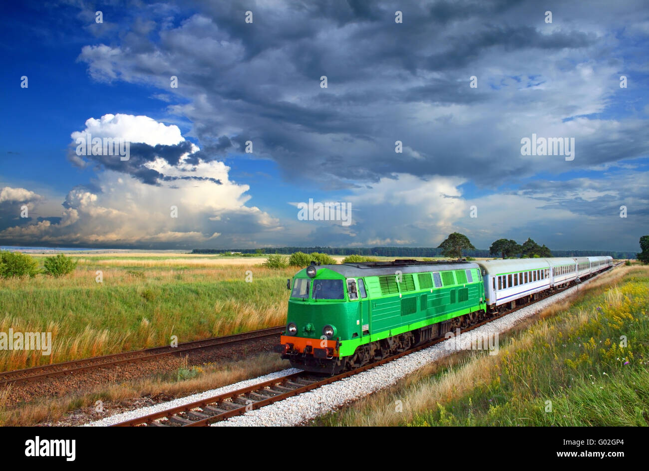 Intercity train passing through countryside with colorful sky over ...