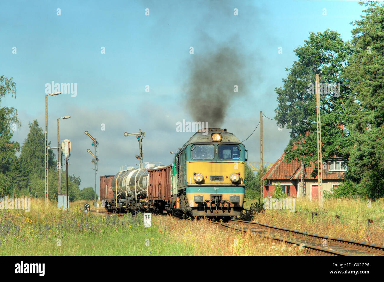 Rural summer landscape with freight train starting from the station ...