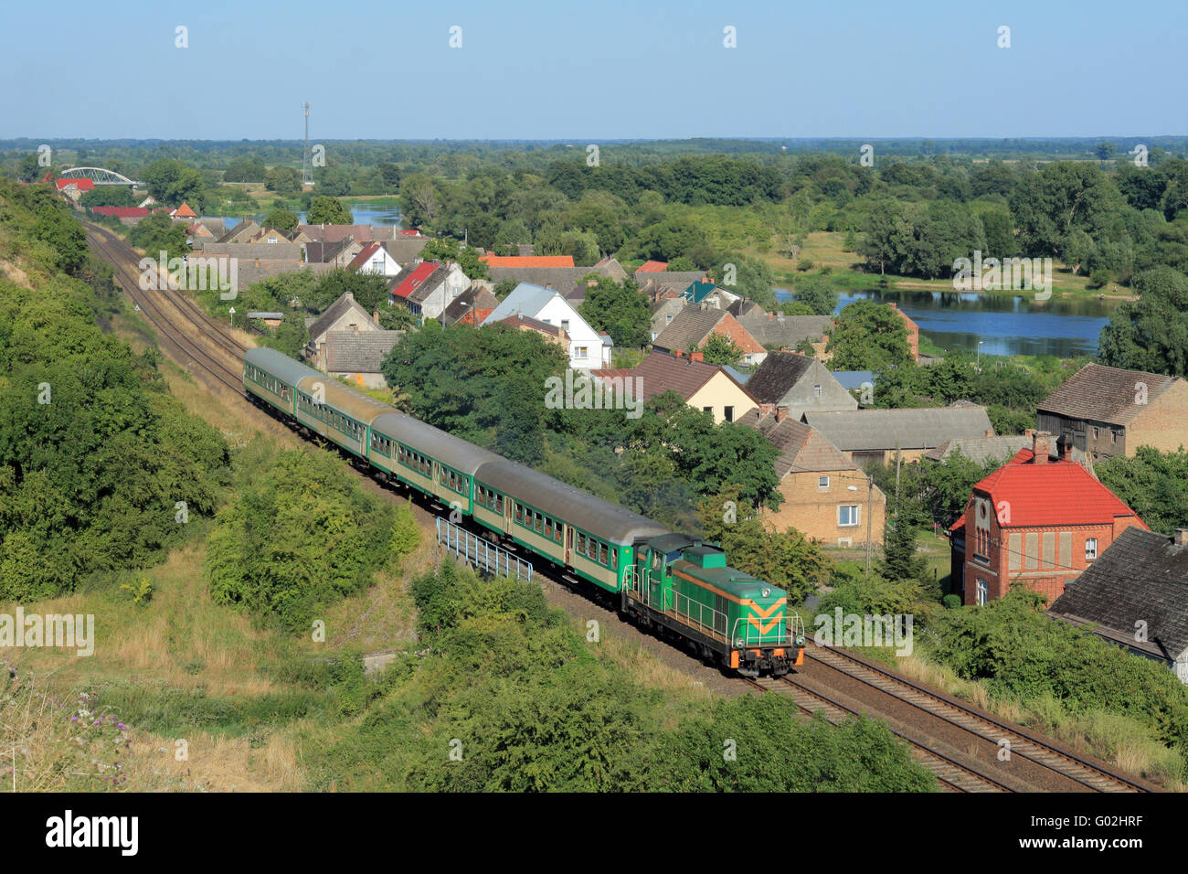 Passenger train passing the village with the river in background Stock ...