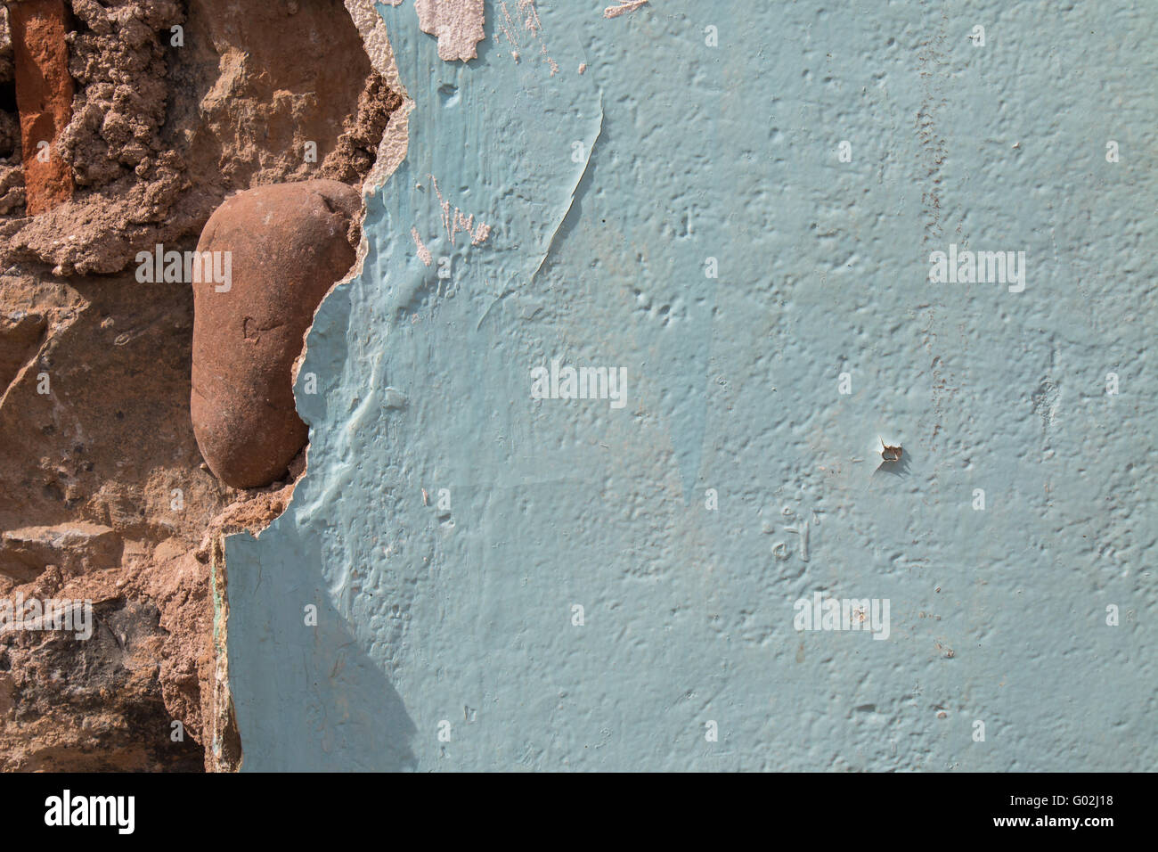 Broken blue painted wall, visible concrete base together with a big ...
