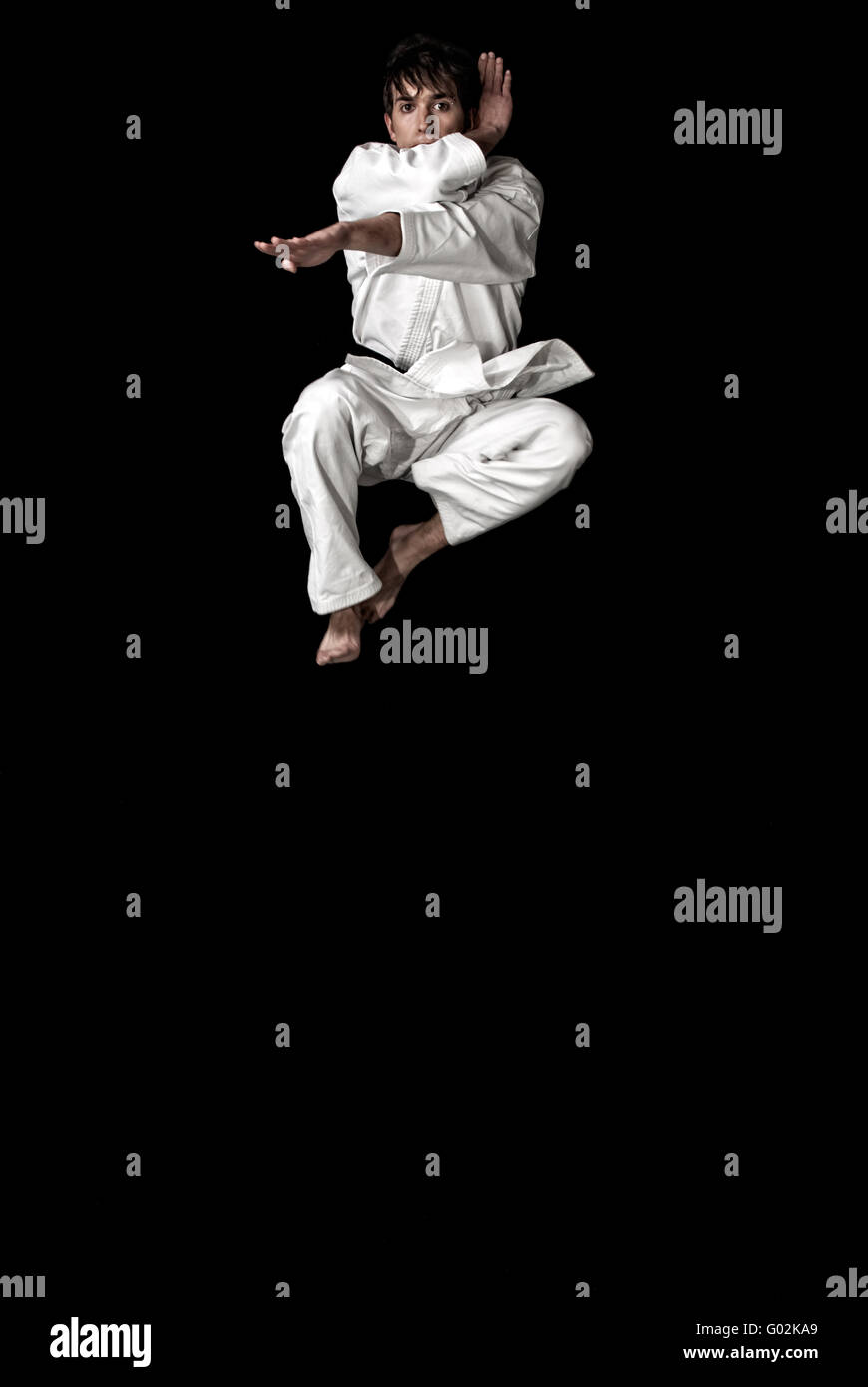 High Contrast karate young male fighter jumping on black background ...