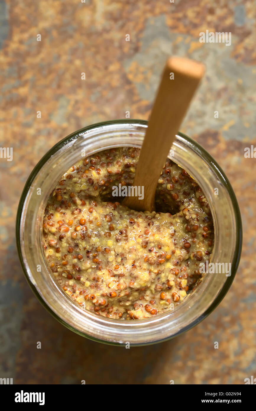 Whole grain mustard in glass jar, photographed overhead on slate ...