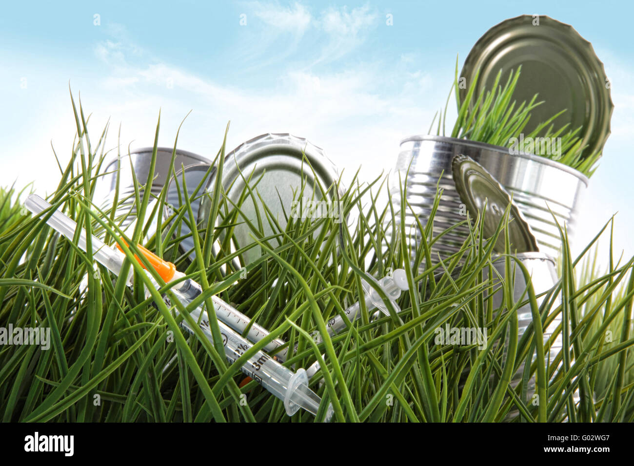 Syringe needles and food cans left in the grass Stock Photo - Alamy