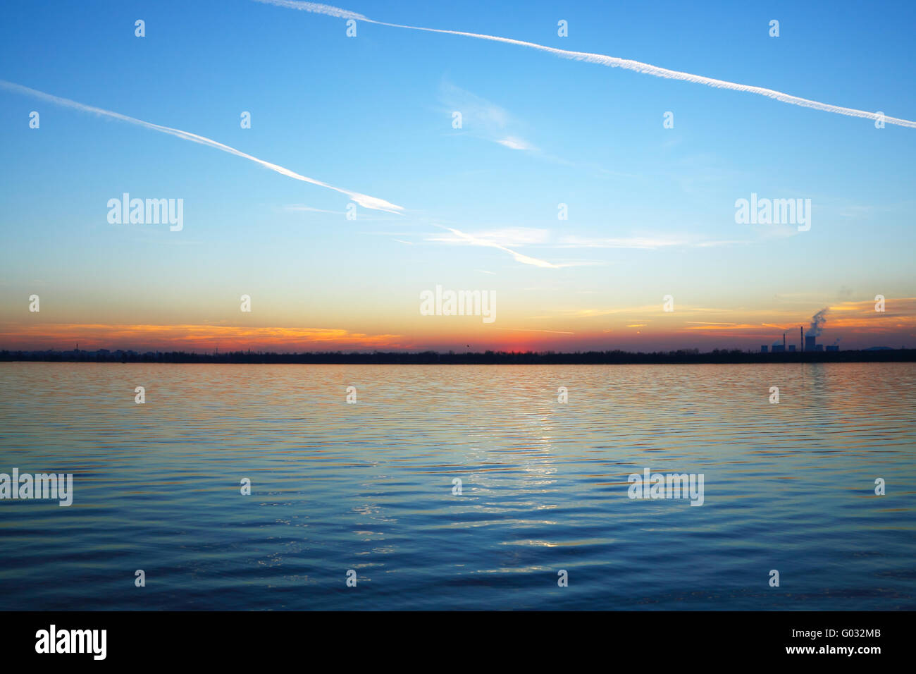 Sunset over the lake and a factory on the horizon Stock Photo - Alamy