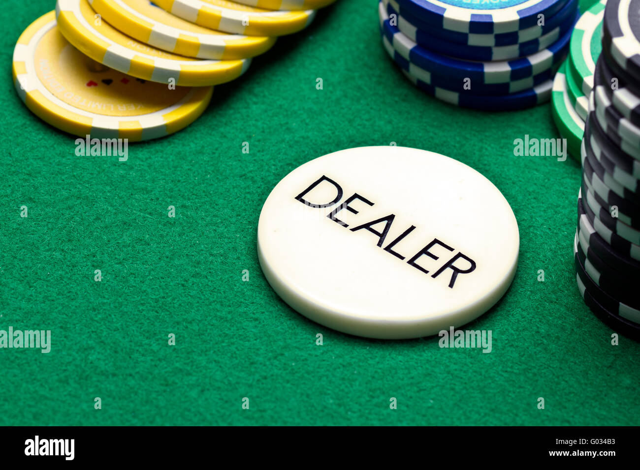 Poker dealer button and chips Stock Photo - Alamy