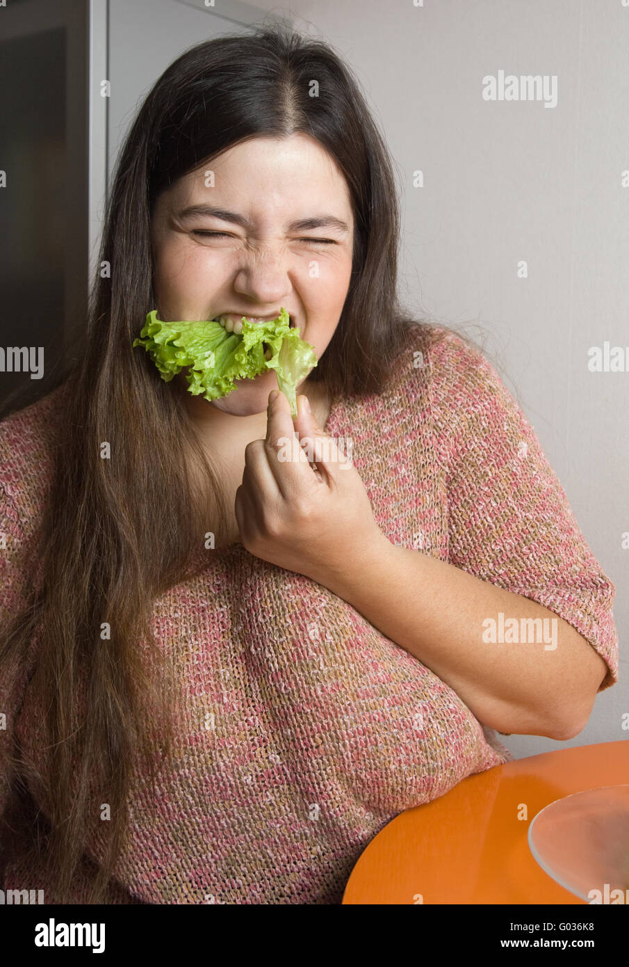 Stout woman trying to eat a leaf of lettuce Stock Photo - Alamy