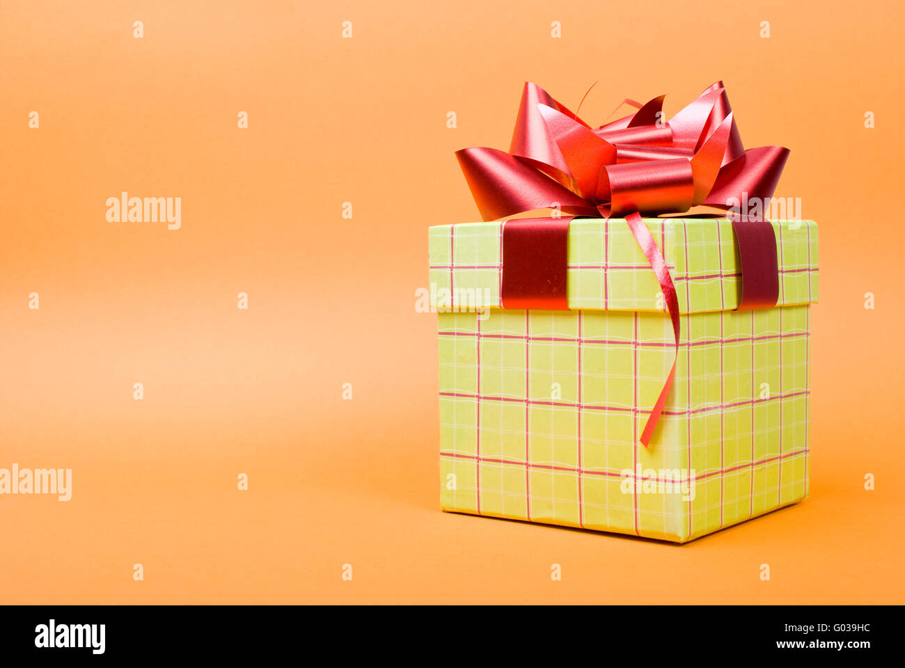 Single green gift box with red ribbon on yellow background Stock Photo ...