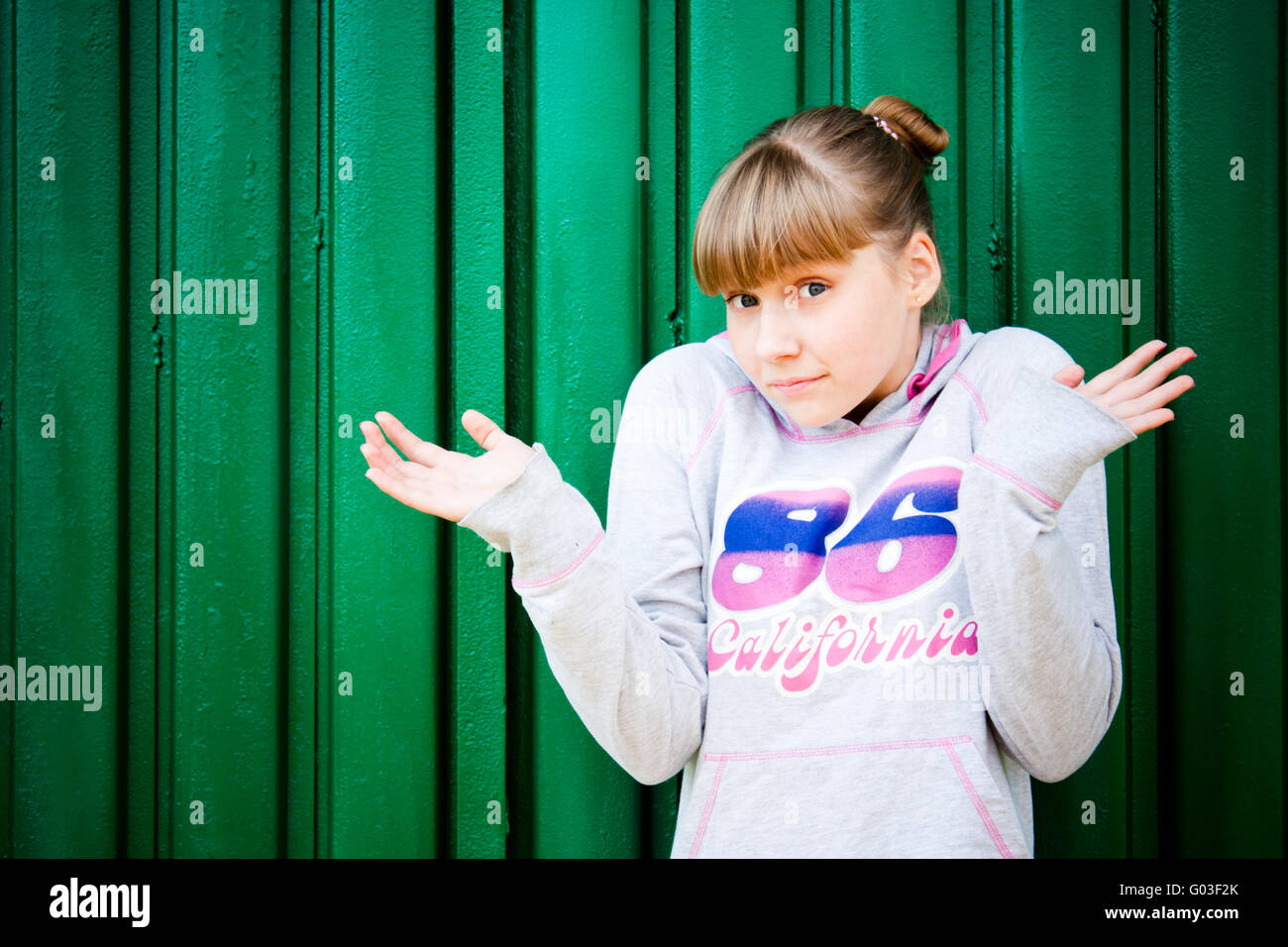 confused teenage girl on a green background Stock Photo - Alamy