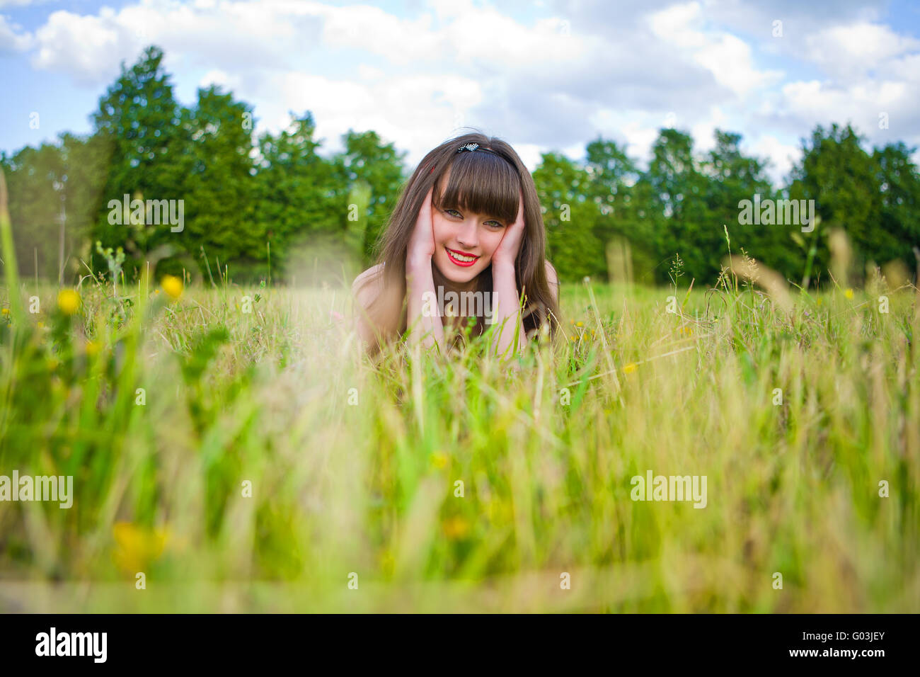 Pretty girl in red sarafan lies on the green grass Stock Photo - Alamy