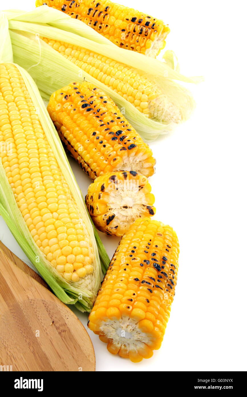 Cleaning freshly roasted ears of corn on cob with green leaves Stock ...