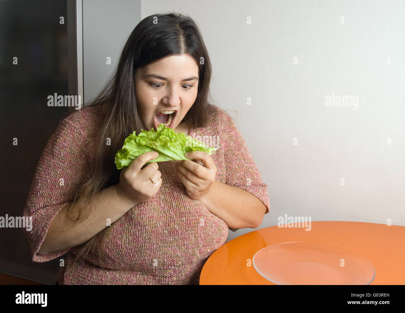Stout woman trying to eat a leaf of lettuce Stock Photo - Alamy