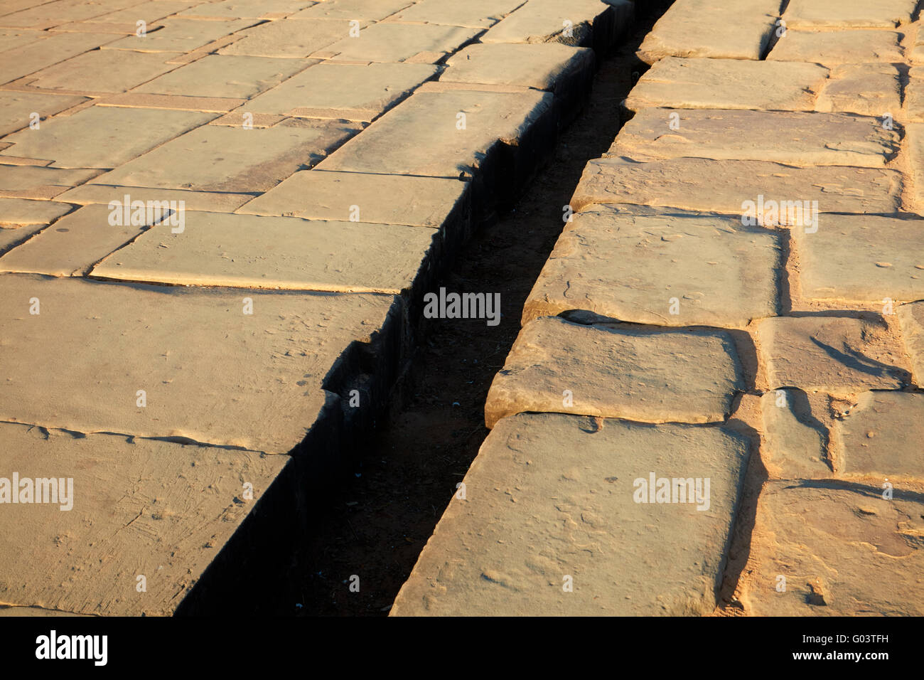 Blocks in ancient sandstone causeway crossing the moat to Angkor Wat ...