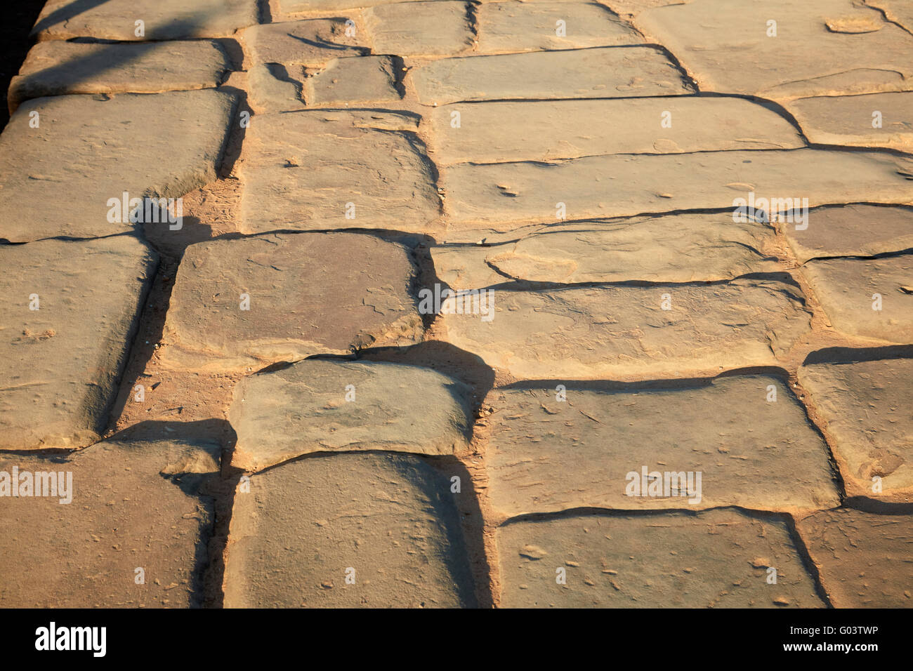 Blocks in ancient sandstone causeway crossing the moat to Angkor Wat ...