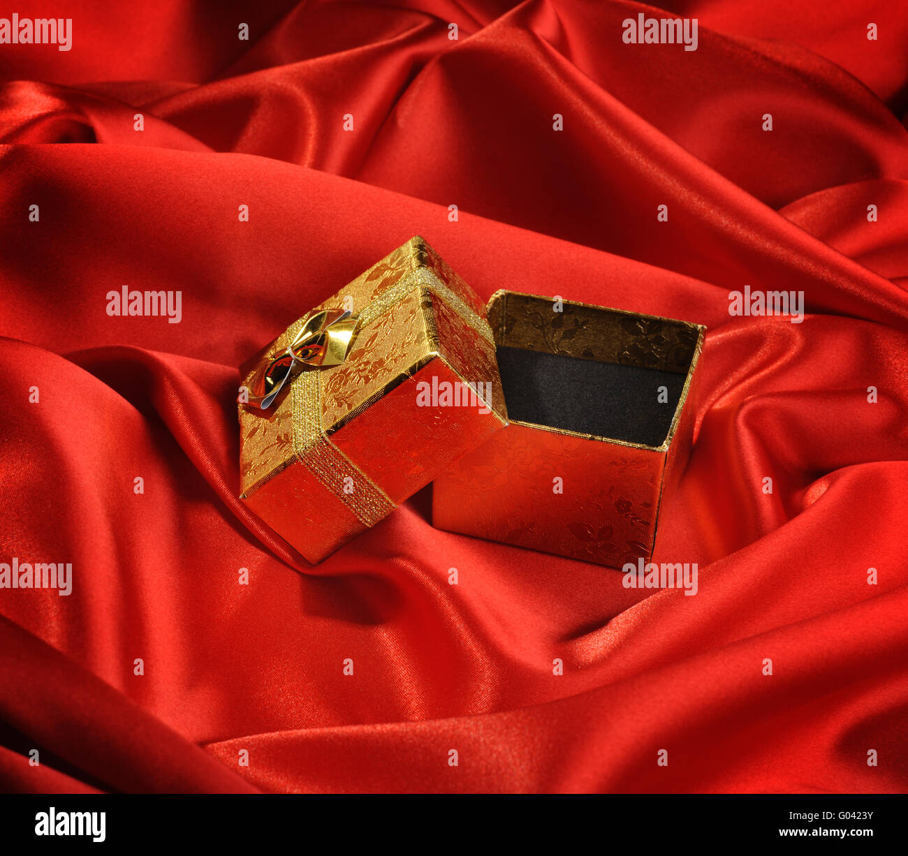 Gold empty boxes with a wedding ring on red silk Stock Photo - Alamy