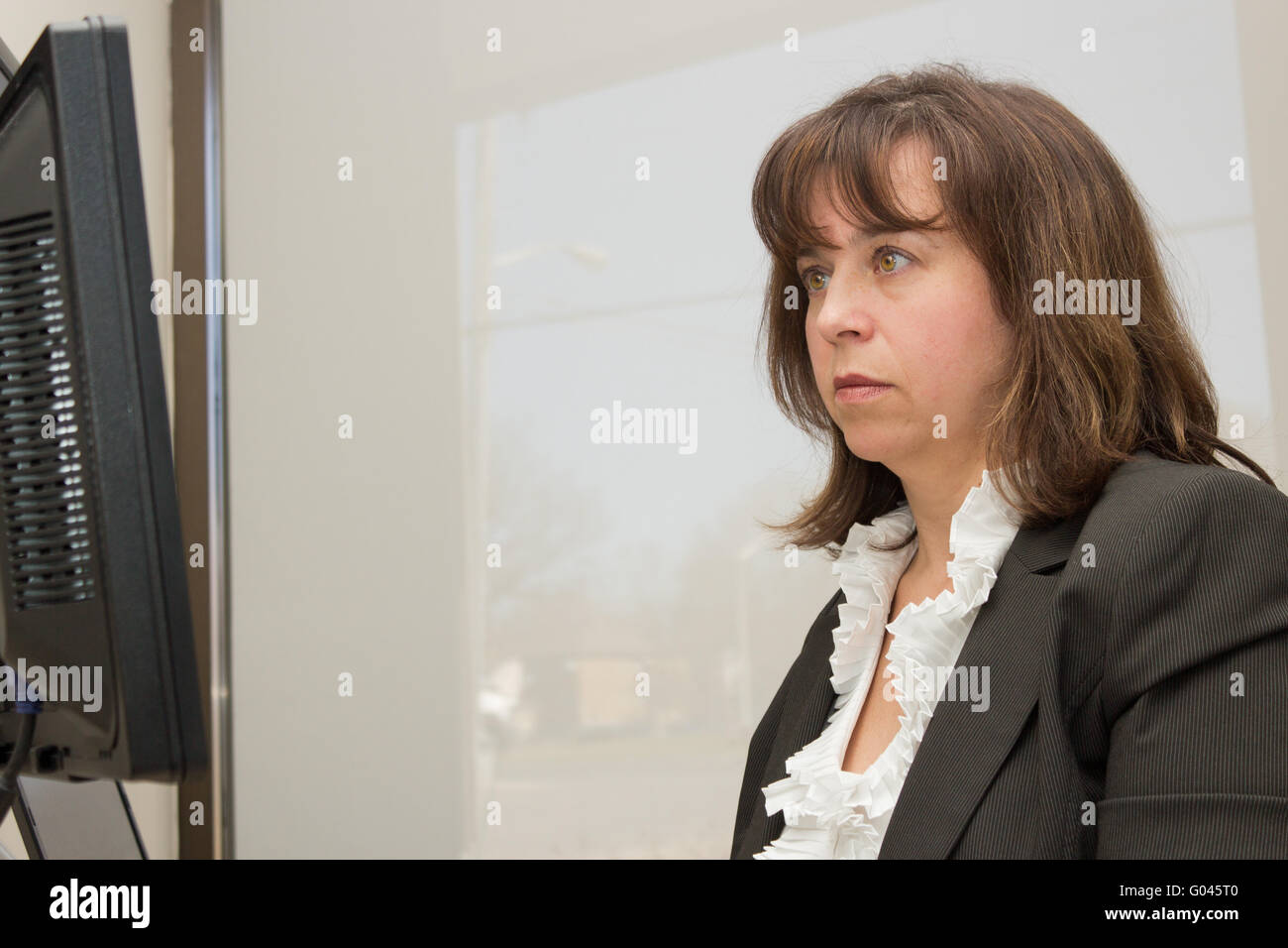 Business woman seated at desk looking at monitor Stock Photo - Alamy