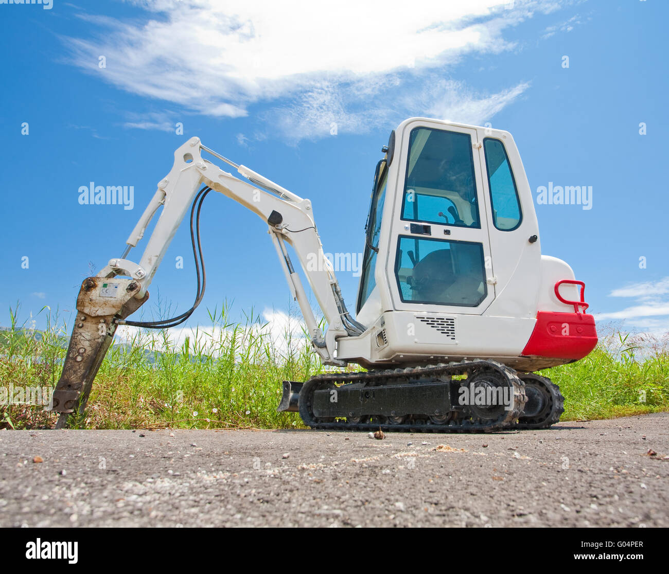 Small caterpillar tractor stands on the asphalt against the blue sky ...