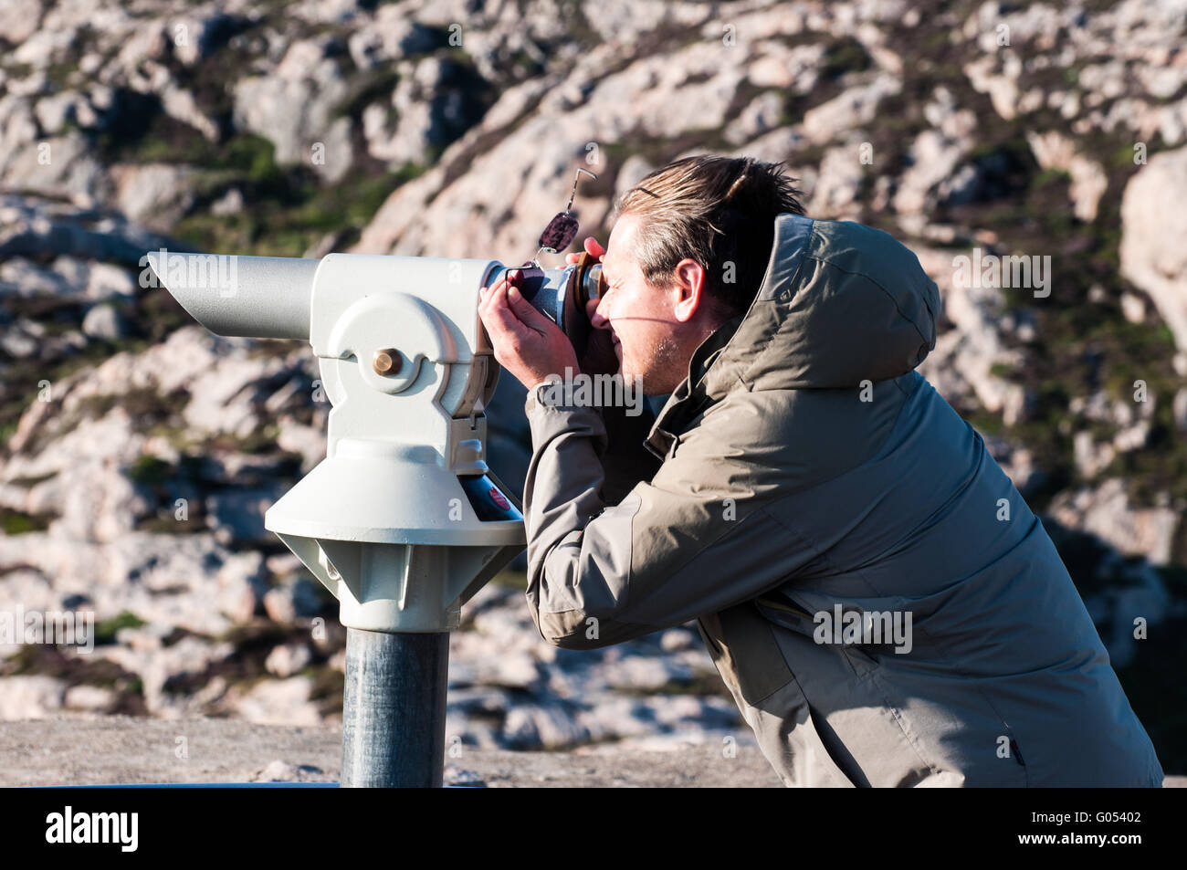 Man observing using spyglass on rocky background Stock Photo - Alamy