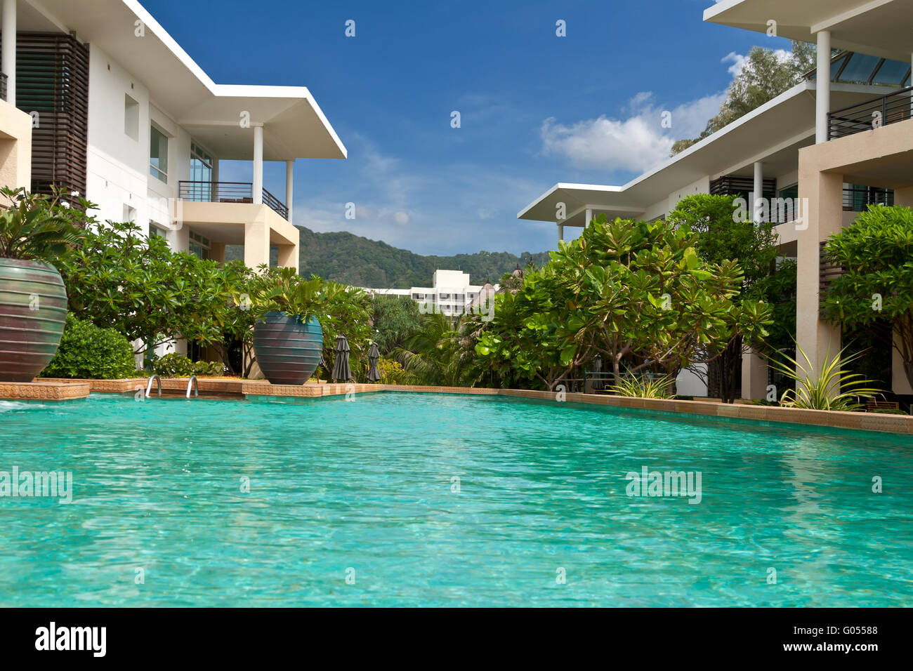 Hotel with sky-blue swimming pool with palm trees Stock Photo - Alamy