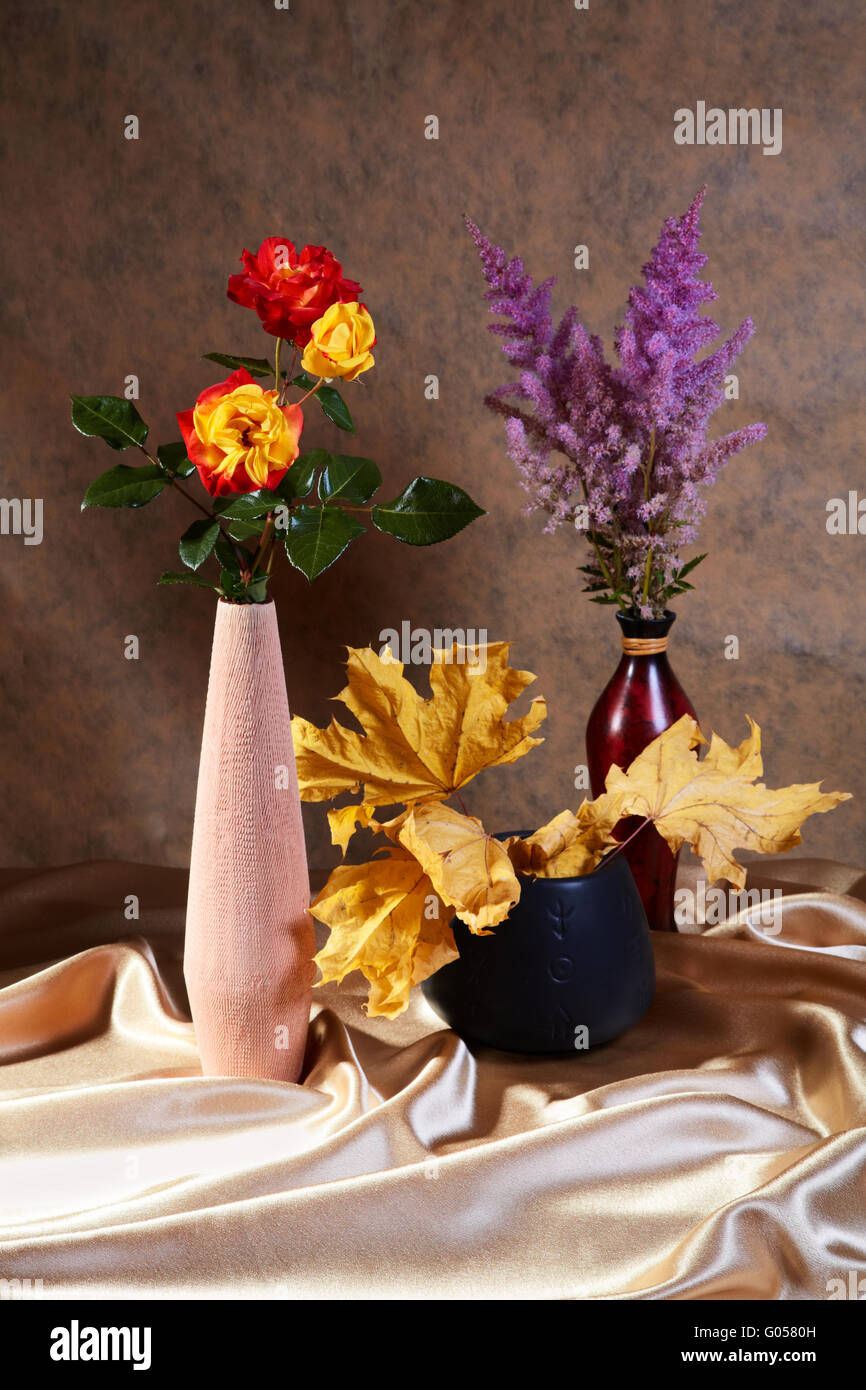 Still-life with roses and dry maple leaves in vases Stock Photo - Alamy