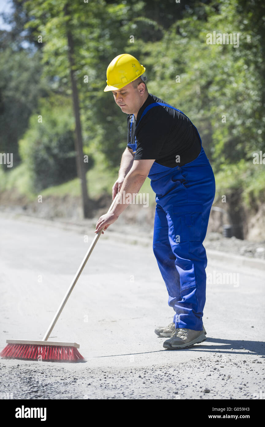 Construction worker cleans the site with a broom Stock Photo - Alamy