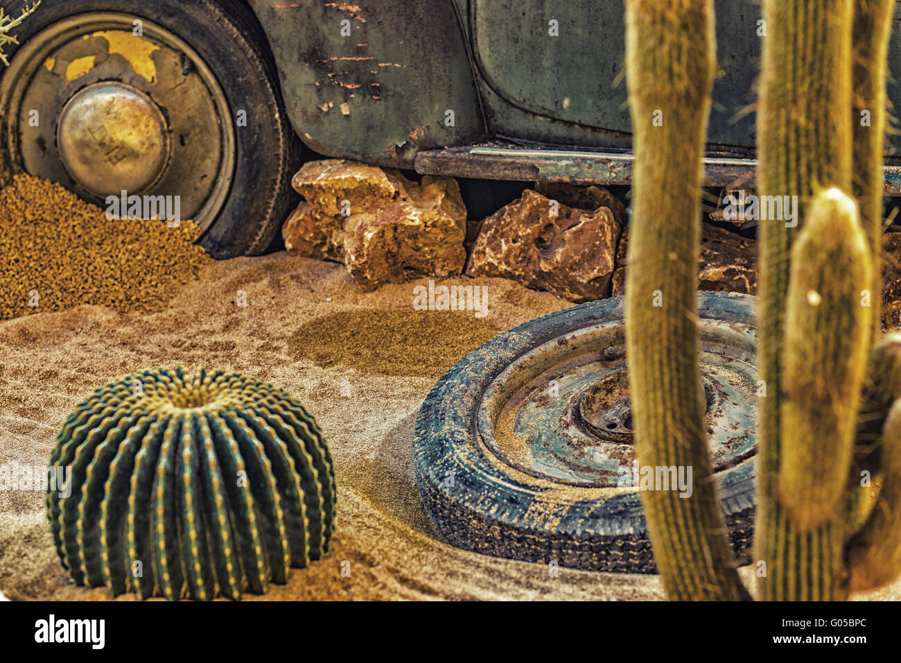 carcass of an old rusty car in the desert sand surrounded by rocks and ...