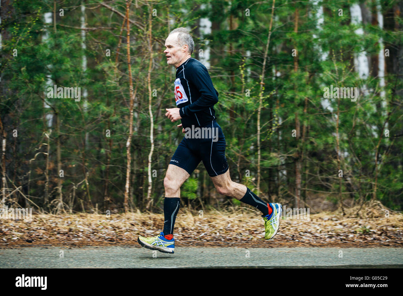 elderly male runner running along road in Park during Half marathon in ...