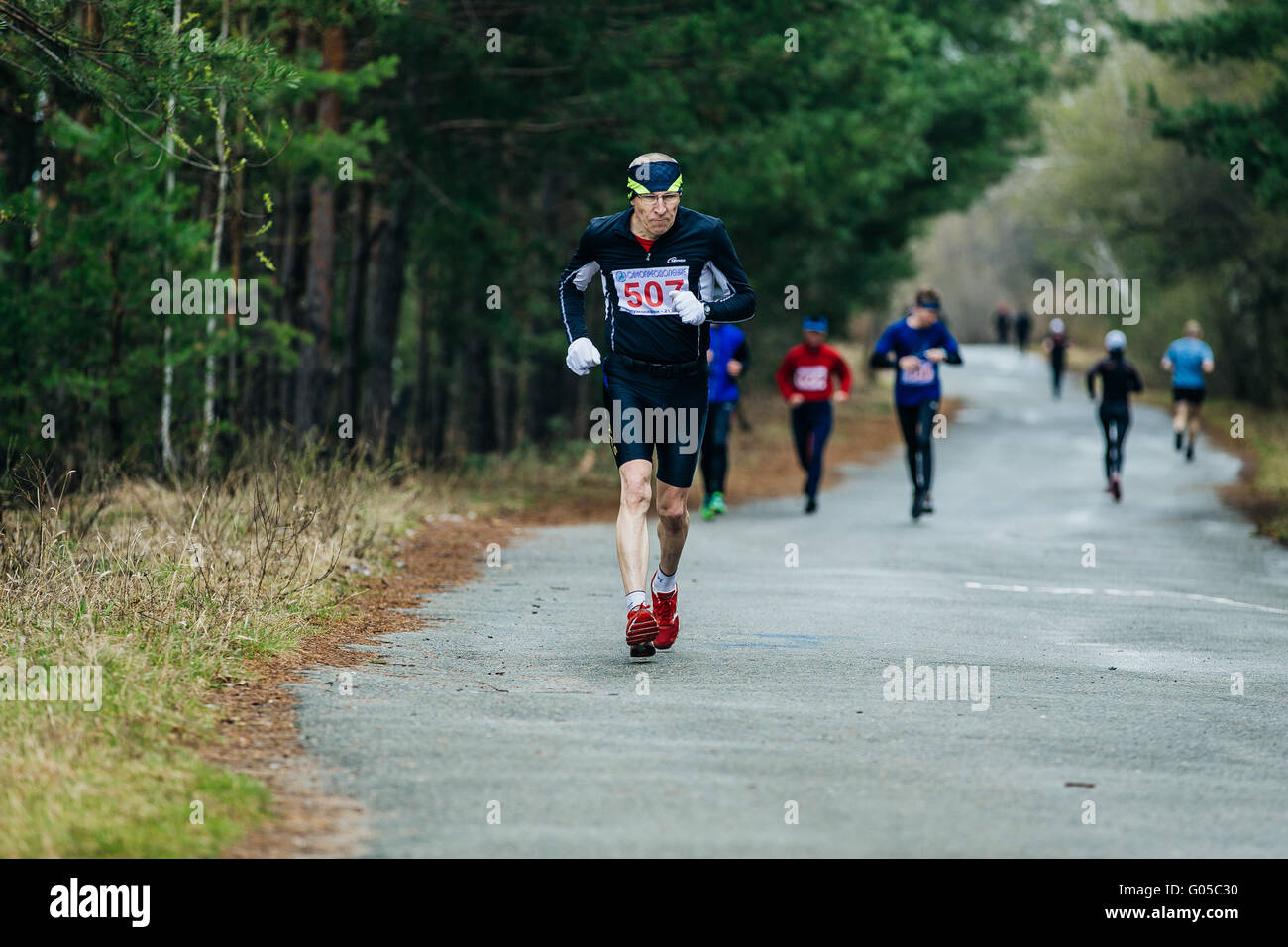 runner middle-aged man running down road in Park during Half marathon ...