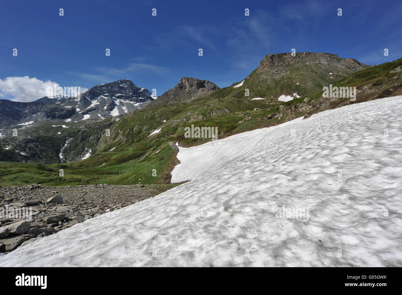 Snow in the summer under the mountains Stock Photo - Alamy