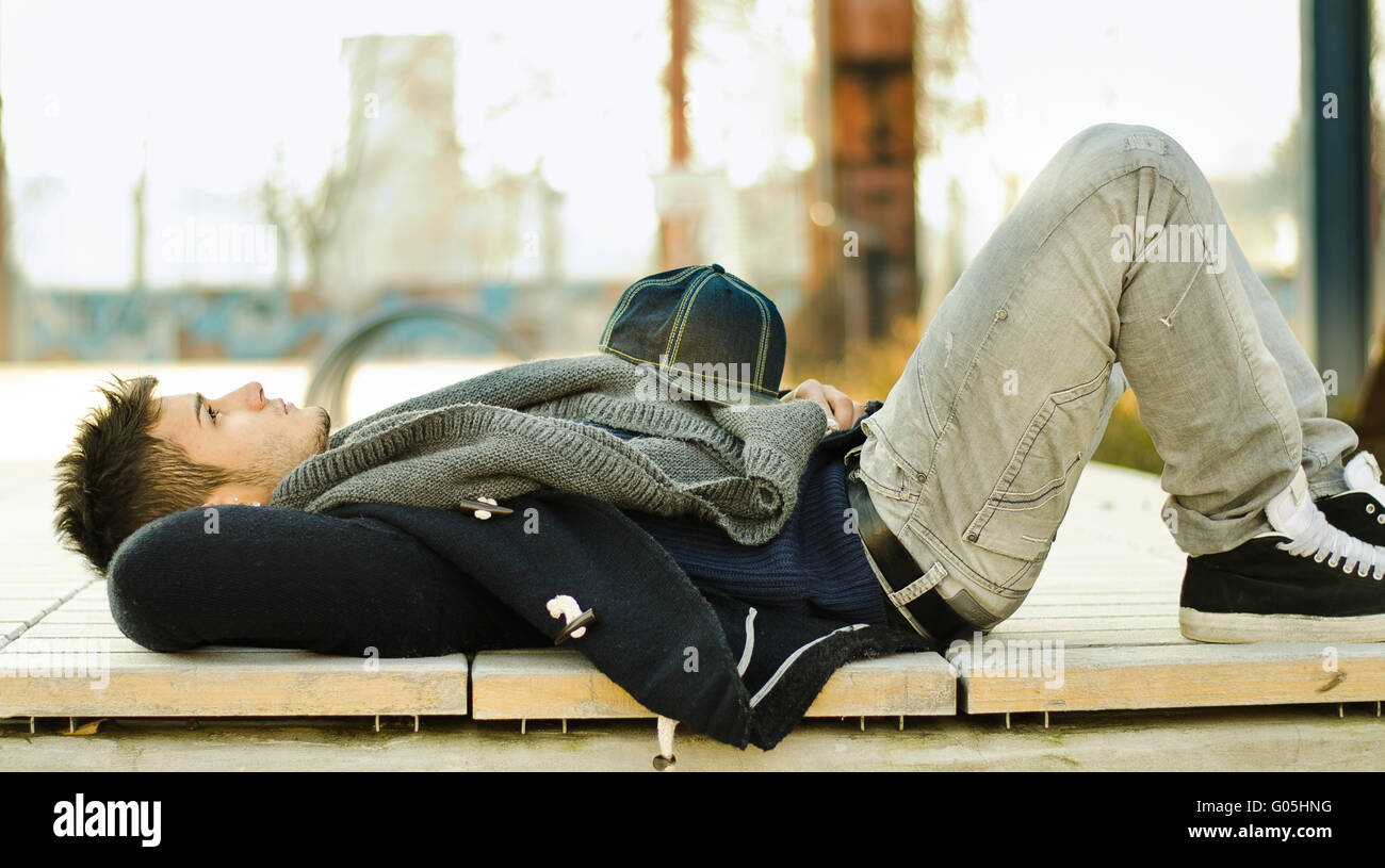 Attractive young man laying on bench Stock Photo - Alamy