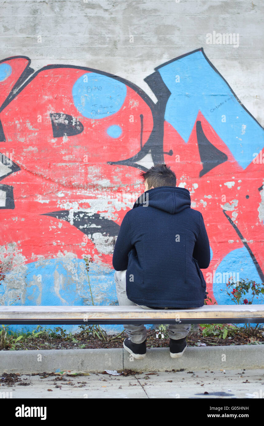 Young man seen from the back looking at a graffiti Stock Photo - Alamy