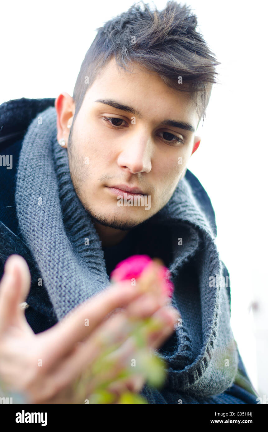 Attractive young man looking at flower Stock Photo - Alamy