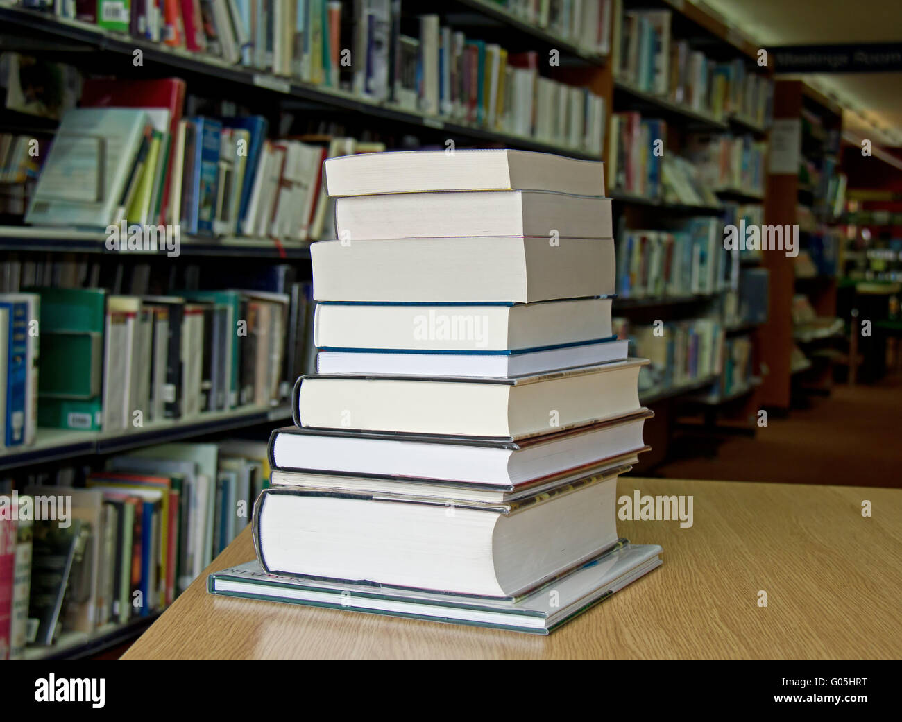 Pile of books in library Stock Photo - Alamy