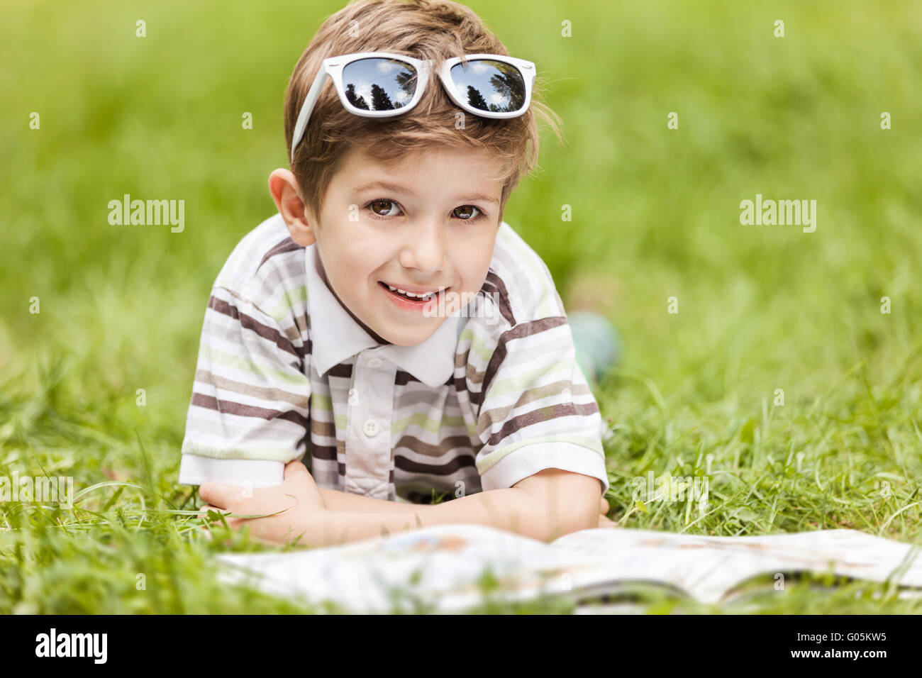 Beauty smiling child boy reading book outdoor Stock Photo - Alamy
