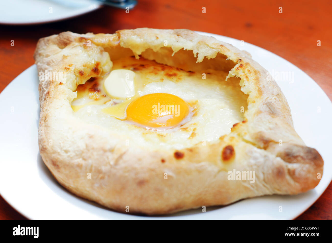 Ajarian or Adjaruli khachapuri, filled with cheese and topped with a ...