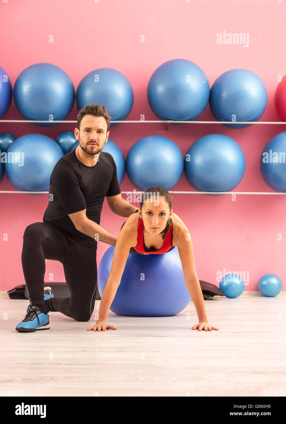 Young woman helped by her coach is training with a ball in a gym Stock ...