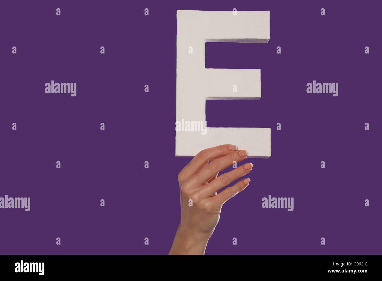 Female hand holding up the letter E from the botto Stock Photo - Alamy