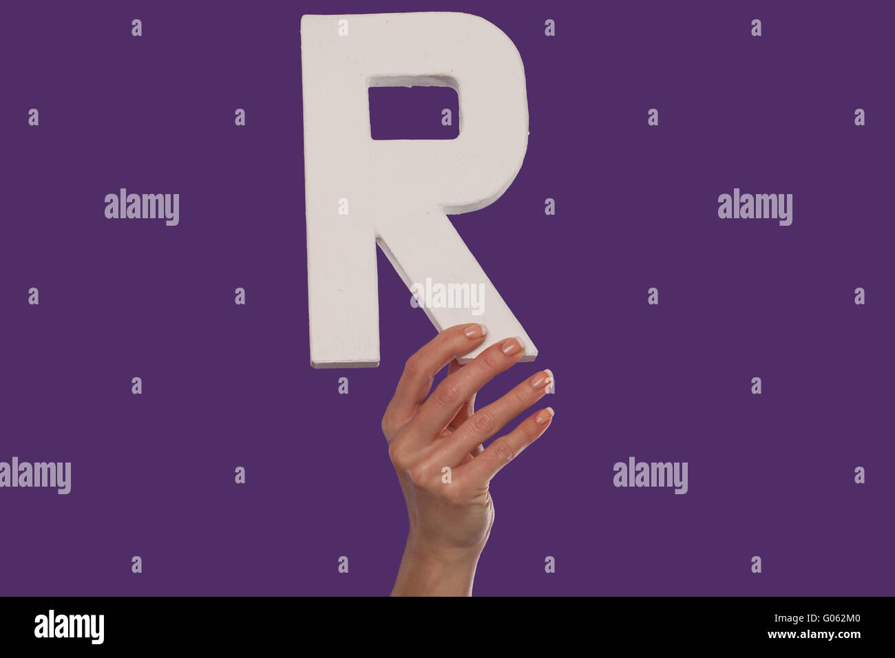 Female hand holding the letter R from the bottom Stock Photo - Alamy
