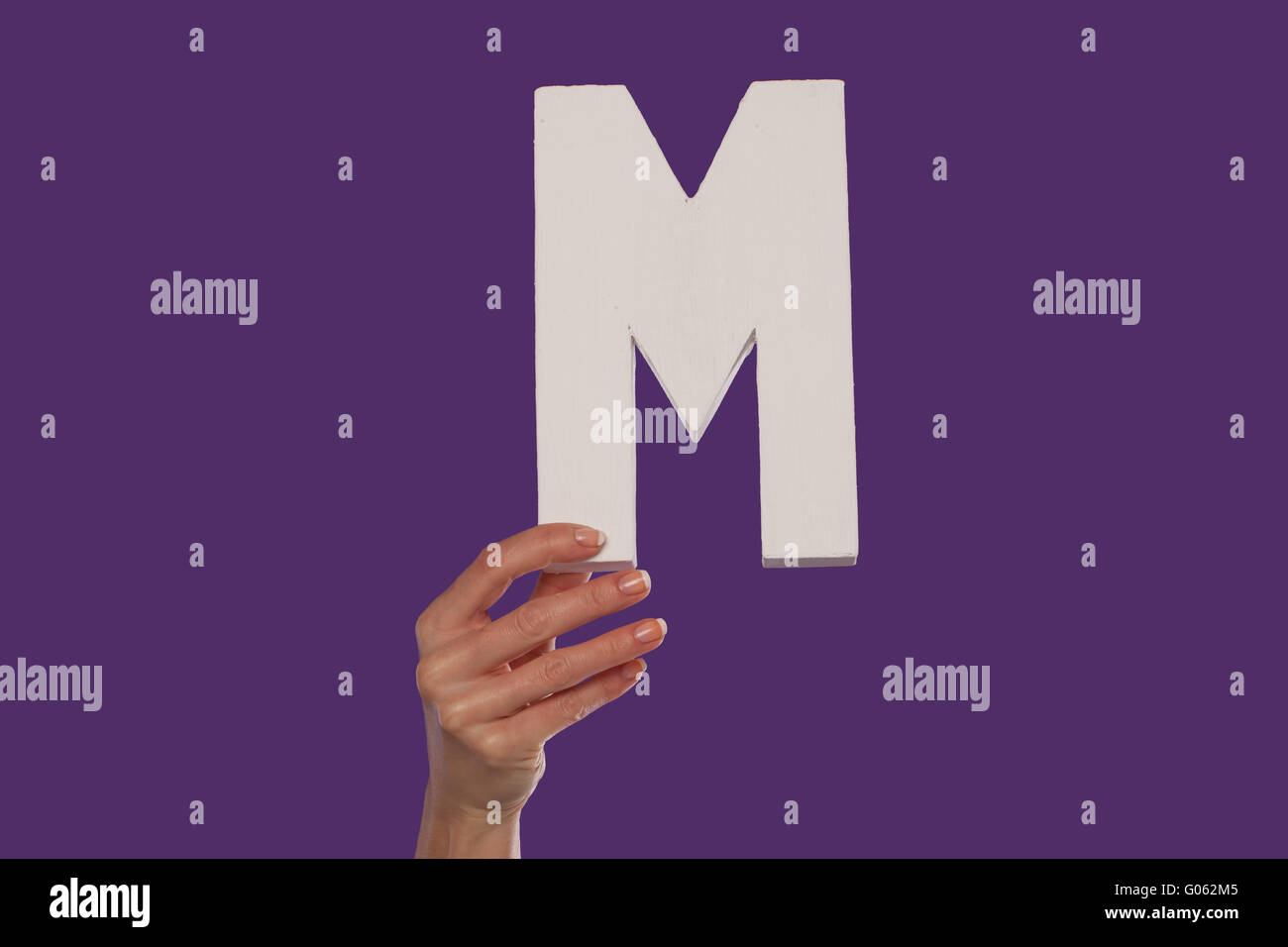 Female hand holding up the letter M from the botto Stock Photo - Alamy