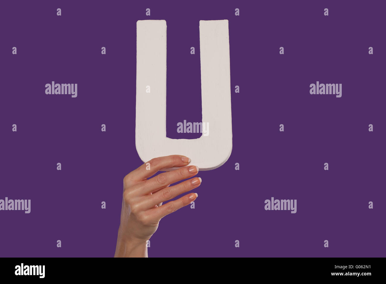 Female hand holding up the letter U from the botto Stock Photo - Alamy